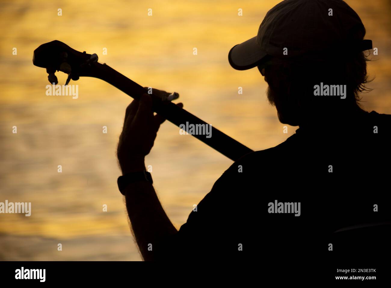 Close-up of a silhouetted man playing the banjo at sunset; Tahaa ...
