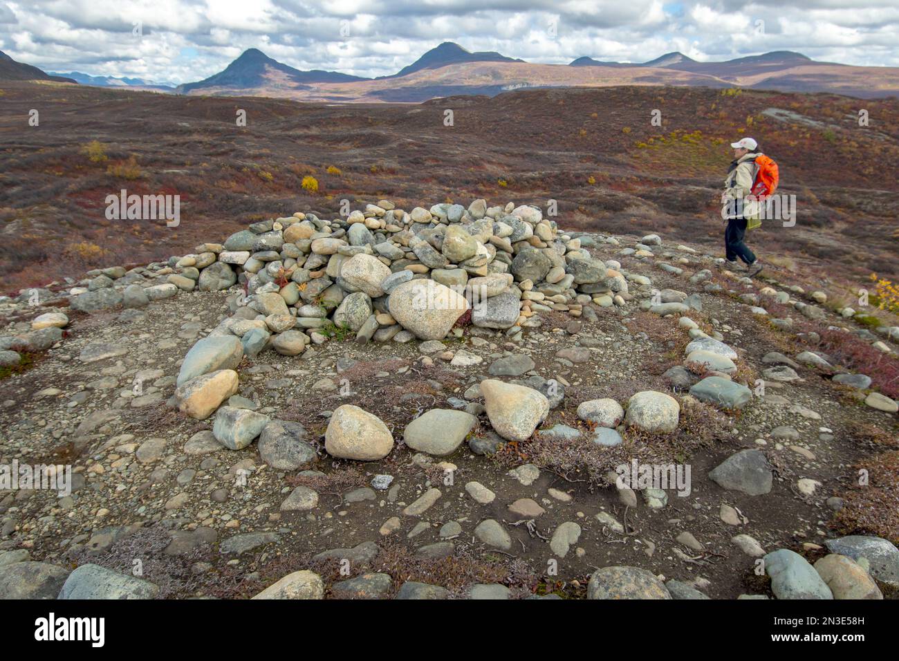 A woman hikes to a hand-made cairn area along a path at Tangle Lakes ...