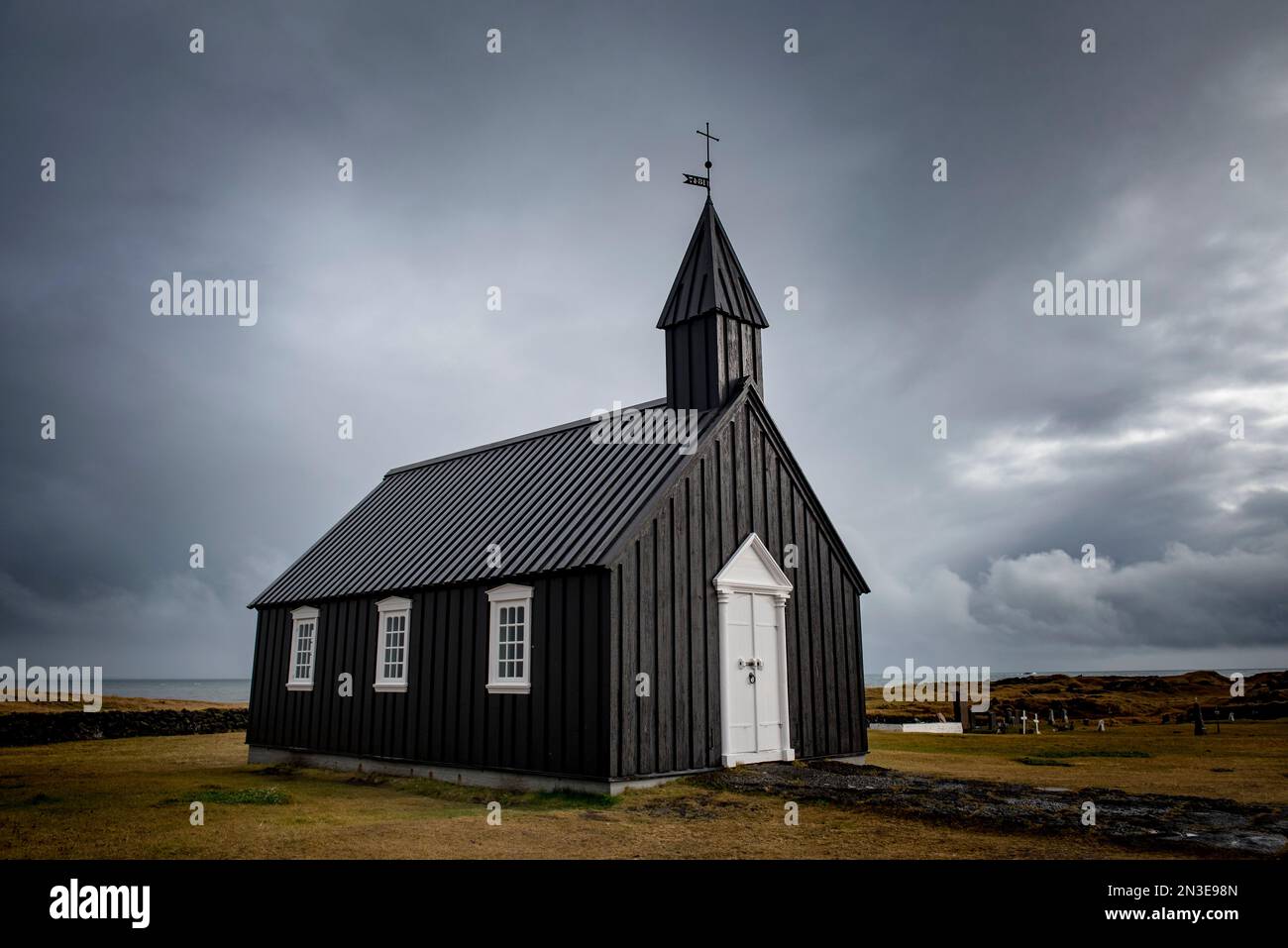 The Black Church of Budir in the coastal countryside with a stormy sky ...
