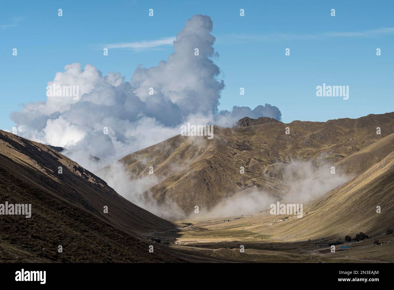 Clouds form in a blue sky over the steam from hot springs along the ...