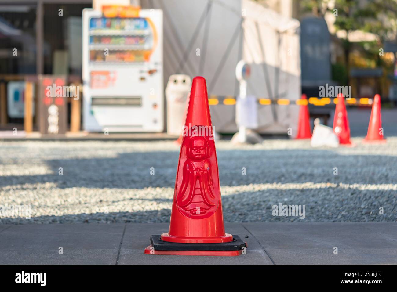 A Japanese red traffic cone adorned with a buddhist jizo bodhisattva ...