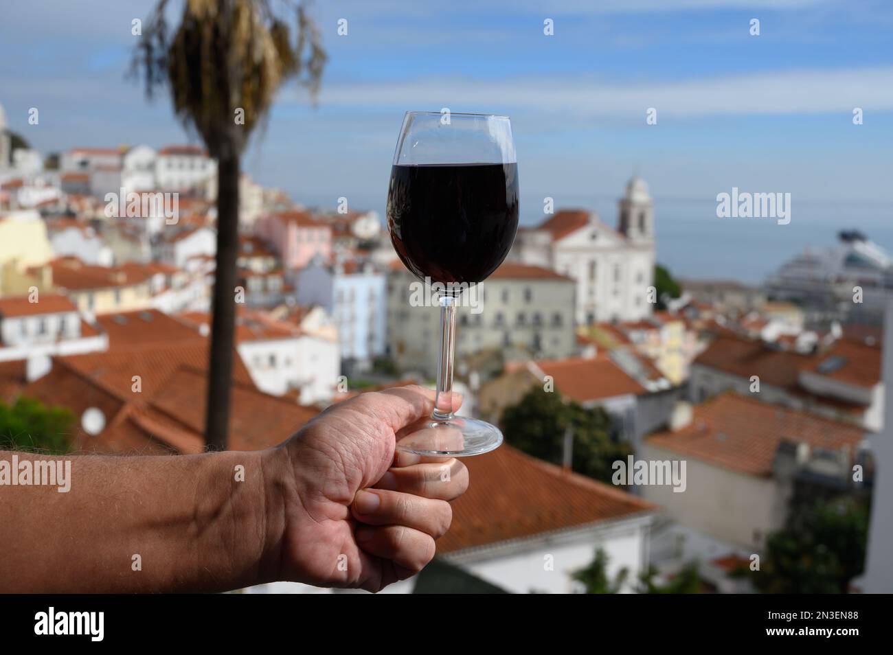 Hand with glass of dry red Portuguese wine in outdoor cafe at view ...
