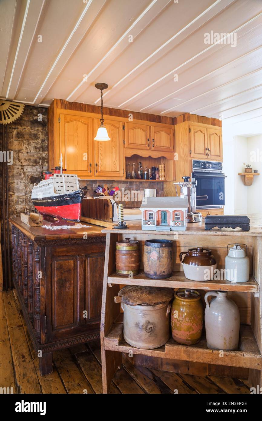 Glazed ceramic pots and jug on wooden shelves in kitchen with oak wood ...