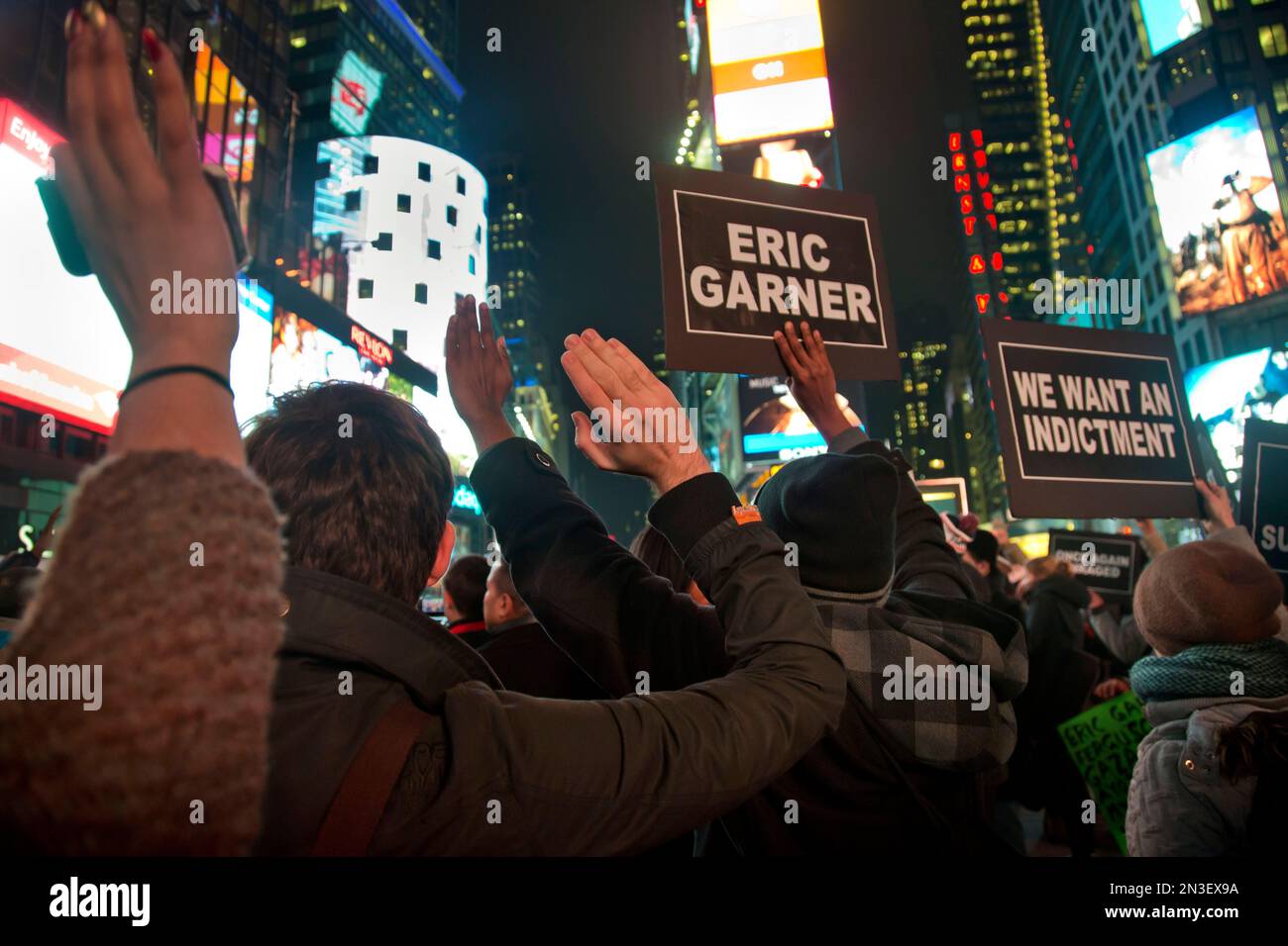 Protesters in Times Square raise their hands and chant while carrying ...