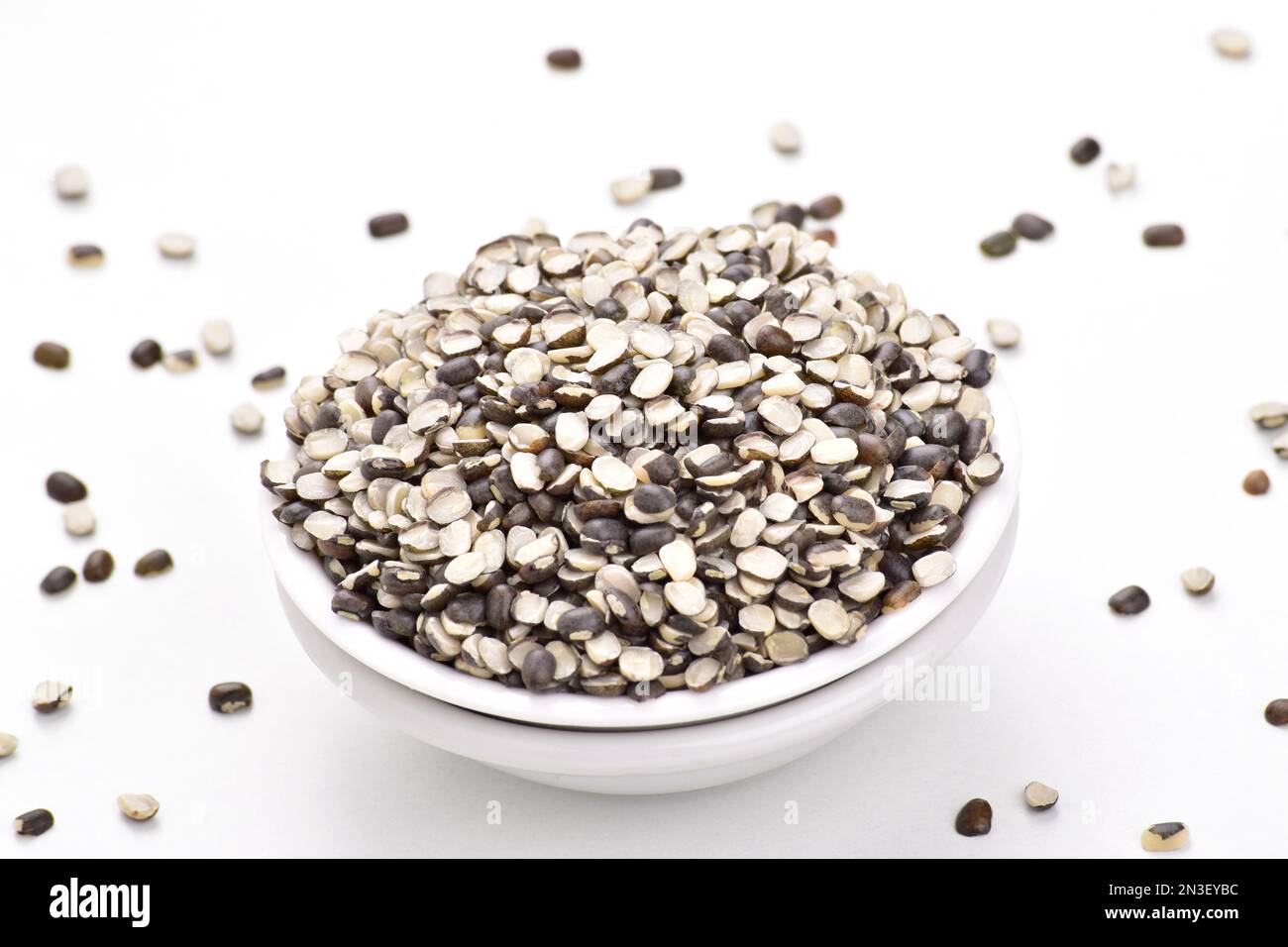 Black split gram in bowl on white background, uncooked urad chilka dal ...