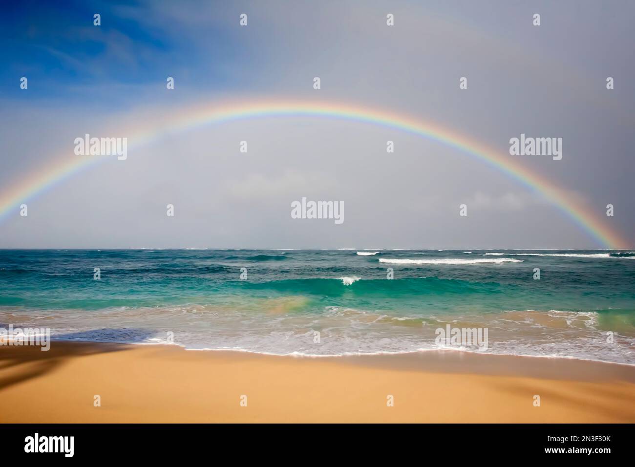 Rainbow spanning the ocean waves at Baldwin Beach on the North Shore of ...