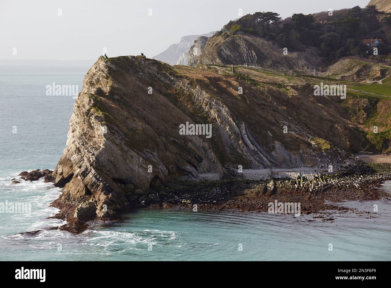 People walking along the beach and the cliff top trails at Lulworth ...
