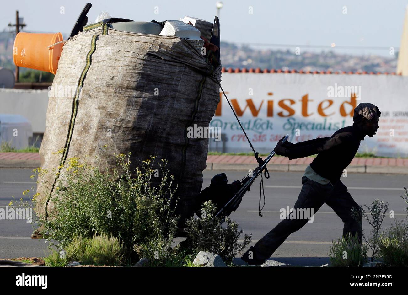 A man pulls an improvised cart filled with metal and plastics scavenged ...