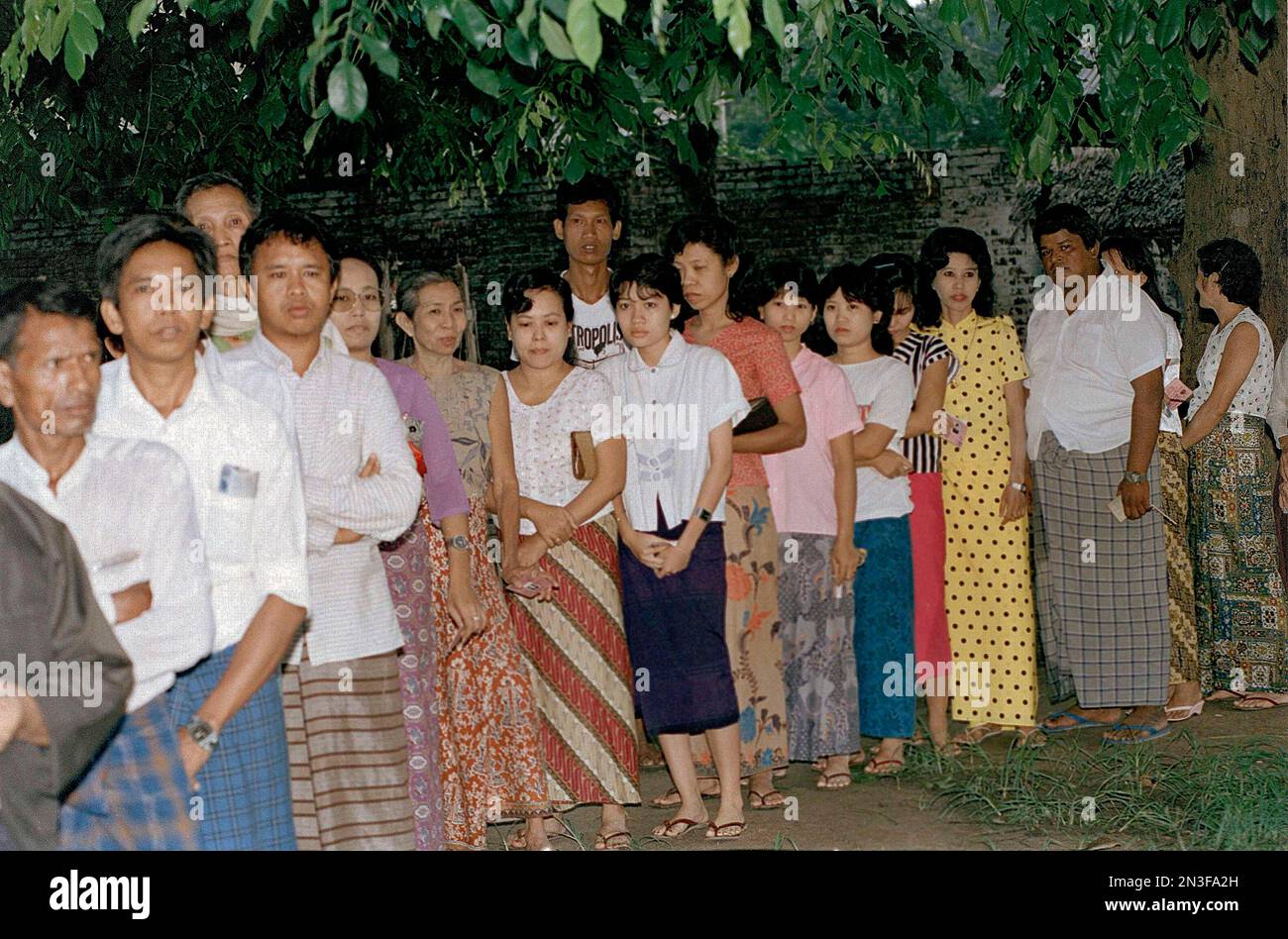 Burmese voters in traditional dress form a long line, waiting for a ...