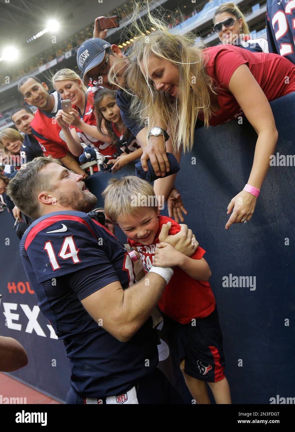 Houston Texans' Ryan Fitzpatrick (14) grabs is children from the stands ...