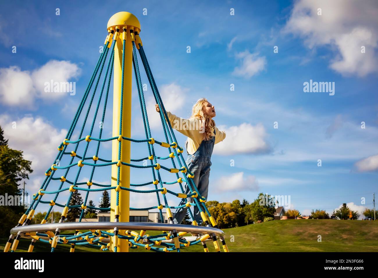 Young girl playing on a merry-go-round in a school playground on a warm ...
