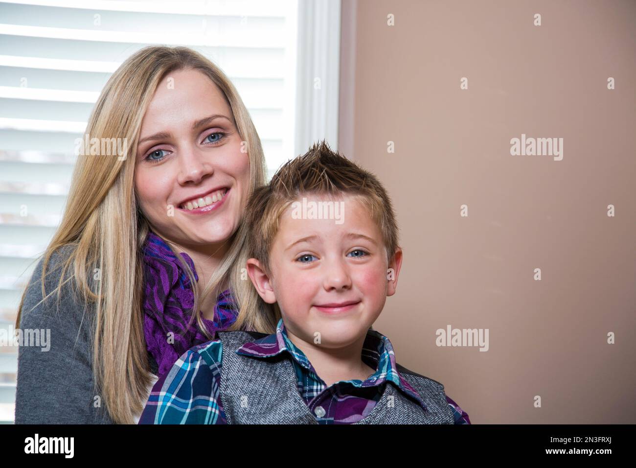 Portrait of young disabled mother with son sitting in her lap at home ...