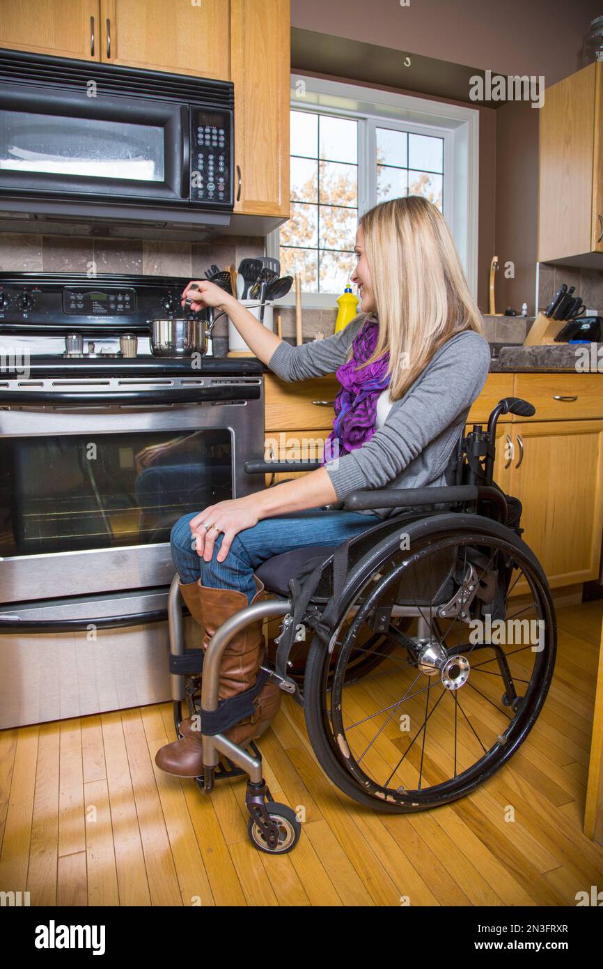 Young disabled woman cooking in the kitchen at home; Spruce Grove ...