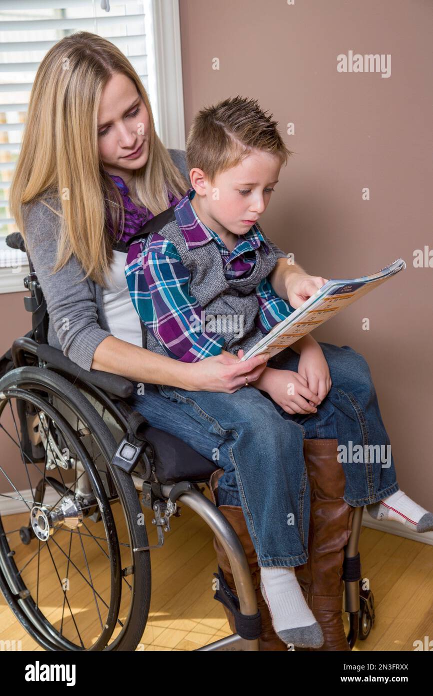 Young paraplegic mother reading a book to her son while sitting in her ...