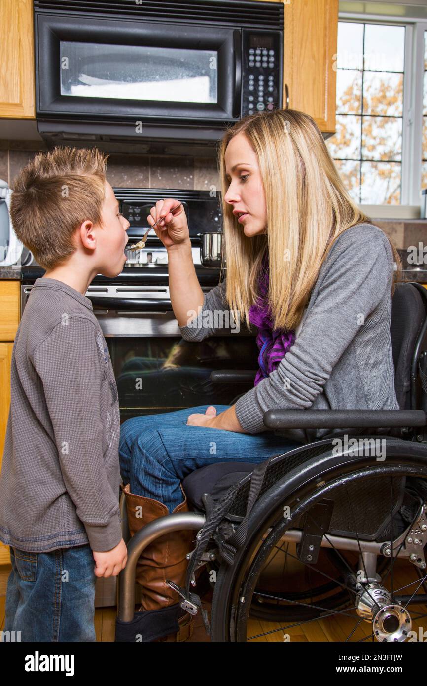 Young disabled mother with her young son while cooking in the kitchen ...