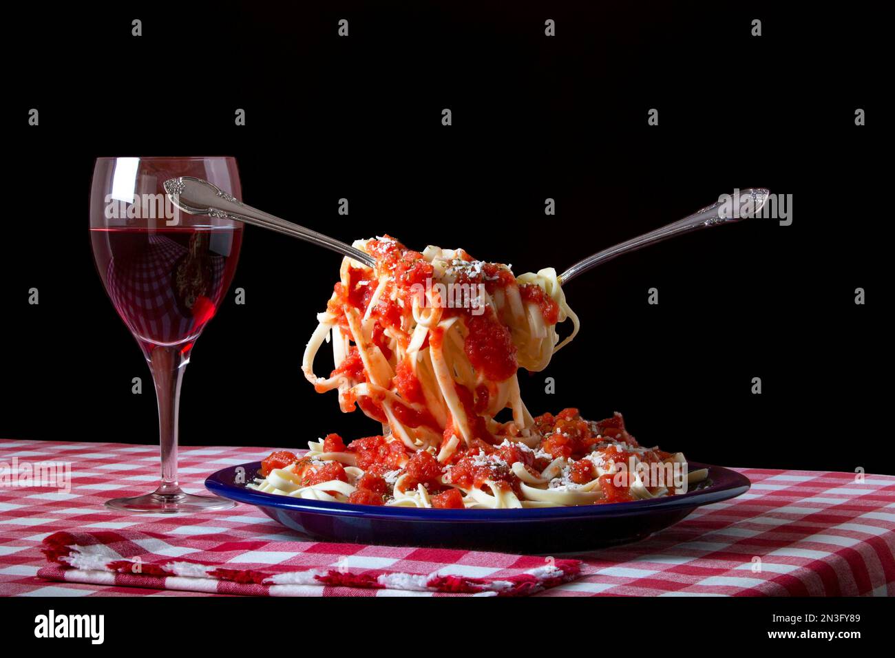 Pasta noodles suspended above a plate of pasta covered with tomato ...
