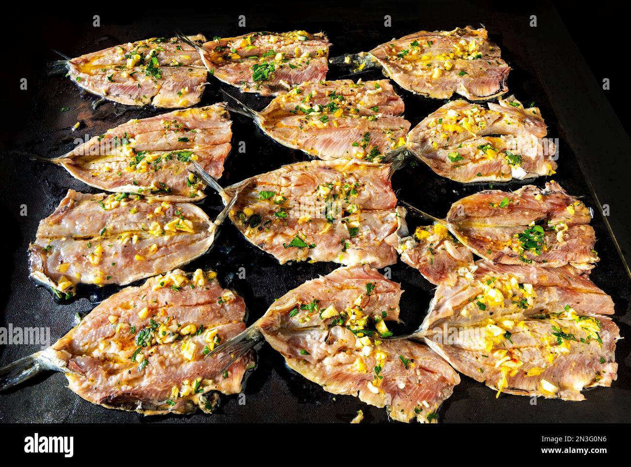 Close up of butterflied fillets of sardines on a barbeque with spices ...