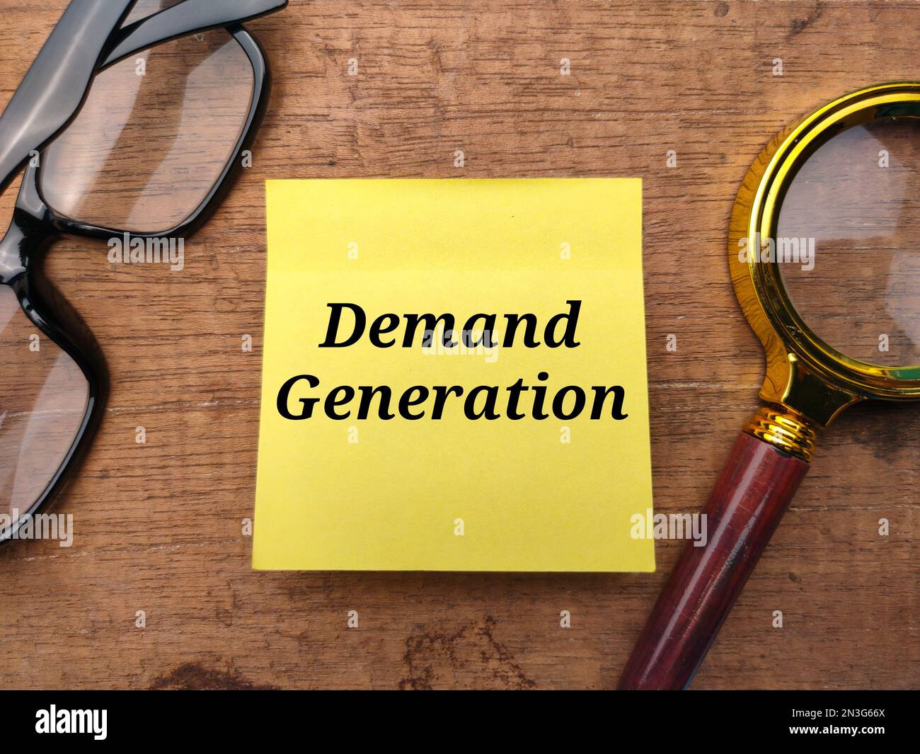 Glasses and magnifying glass with the word Demand Generation on wooden ...