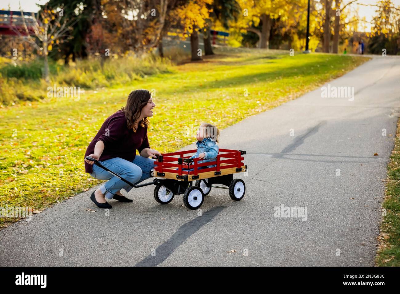 A mother pulling her baby with Down Syndrome in a wagon along a river ...