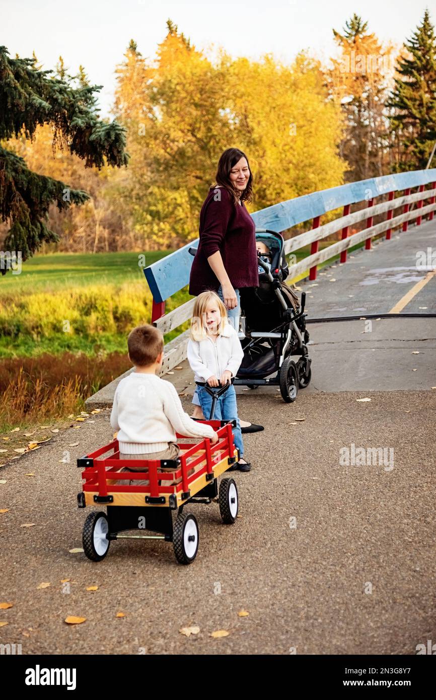 A mother and her young children crossing a bridge over a river in a ...
