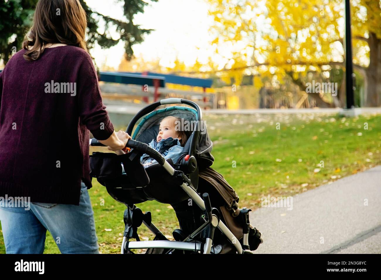 A mother walking with her baby with Down Syndrome in a stroller along a ...