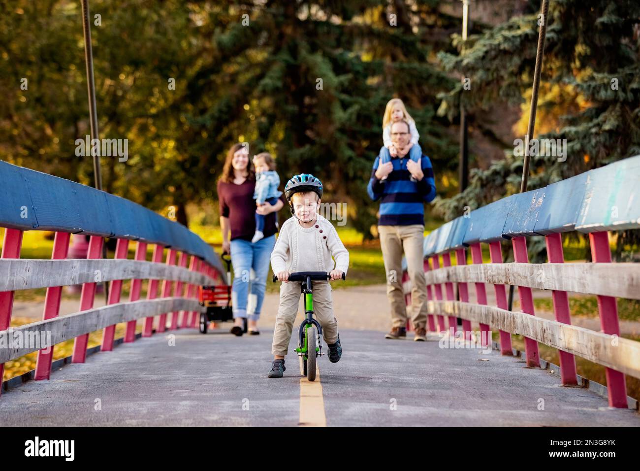 Young family crossing a bridge over a river in a city park during the ...