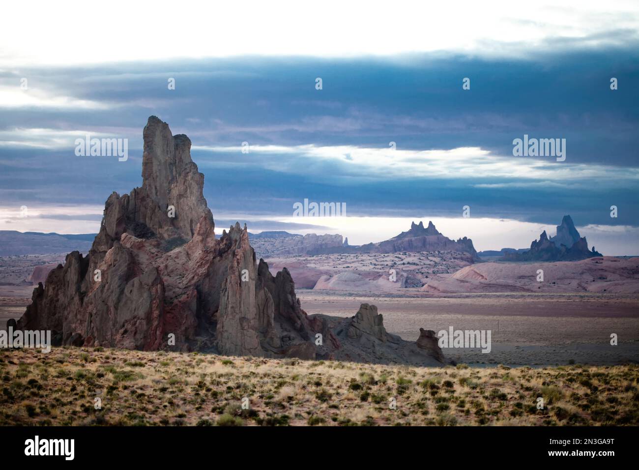 Ship rock stands on the horizon with a similar rock in the foreground ...