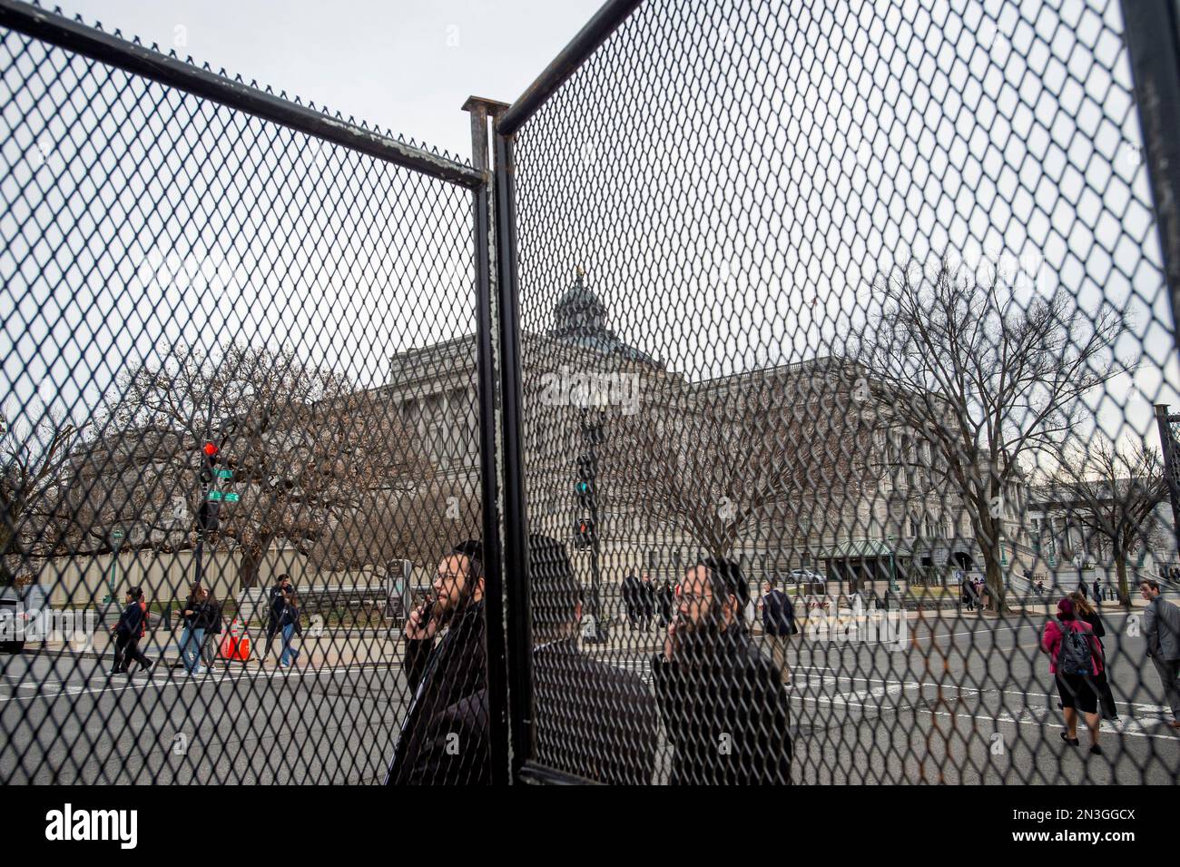 People navigate around a steel fence which surrounds the US Capitol ...