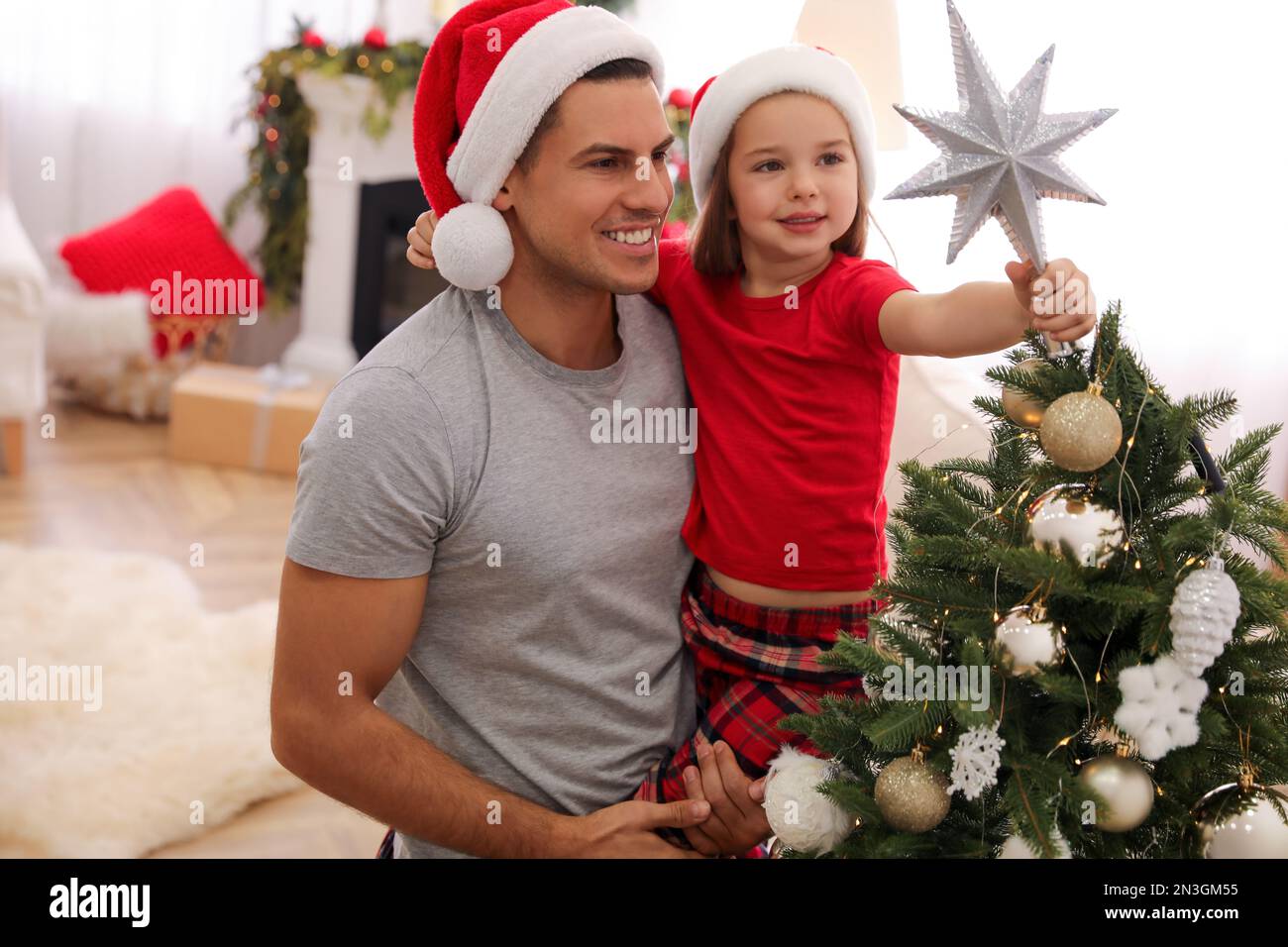 Father and little daughter decorating Christmas tree with star topper ...