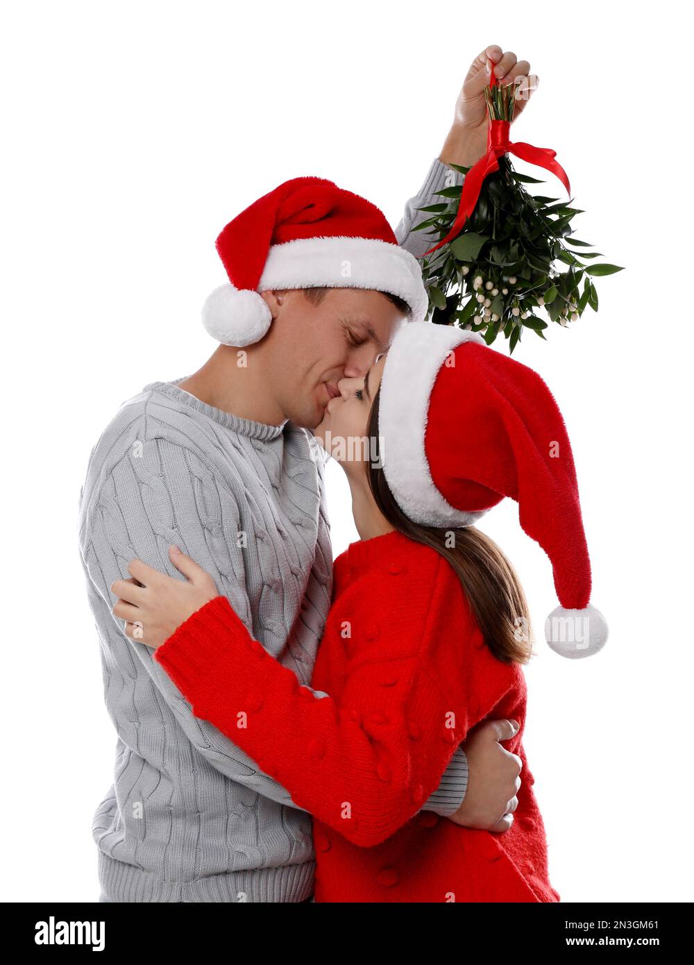 Happy couple kissing under mistletoe bunch on white background Stock ...