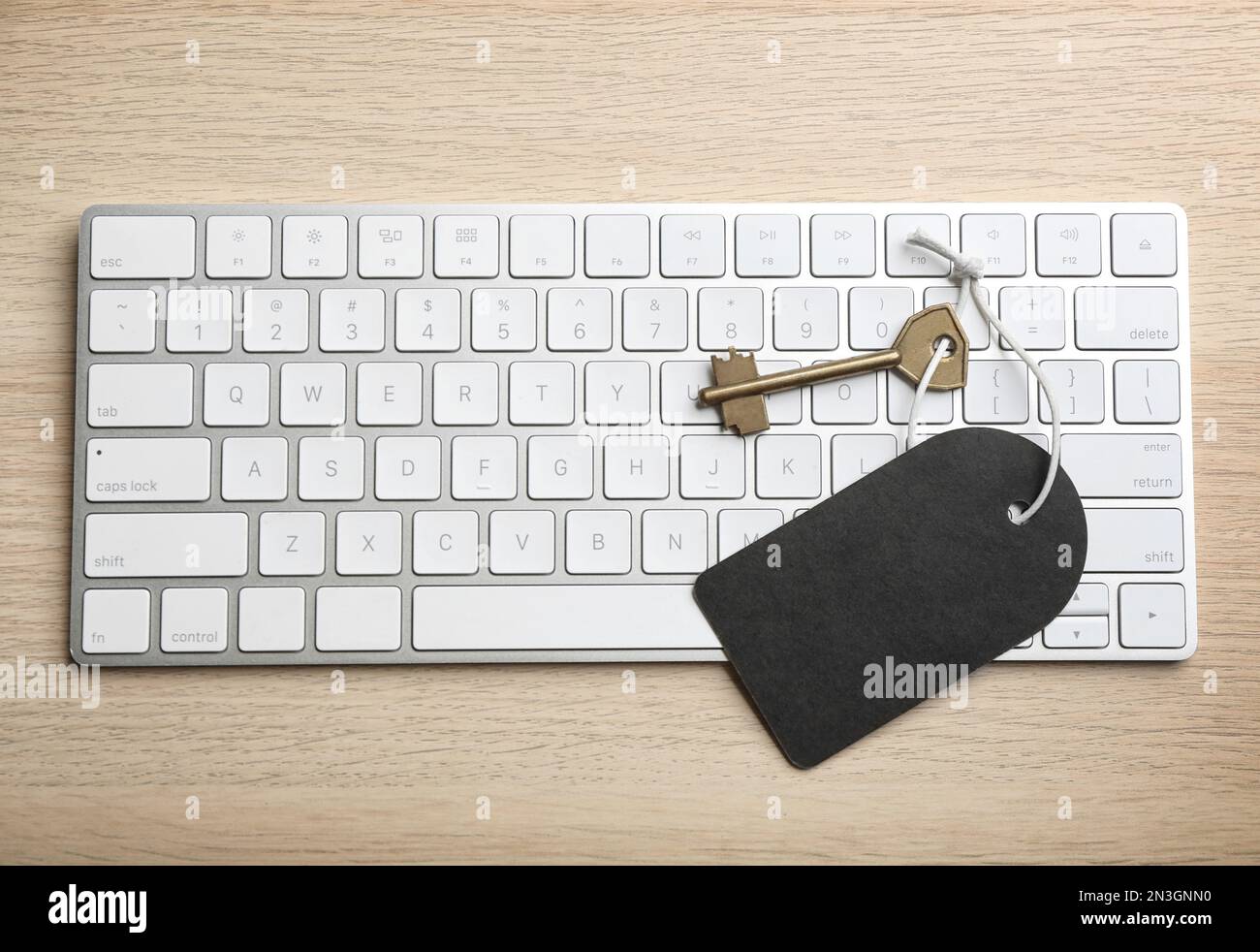Key with blank tag and computer keyboard on wooden table, top view ...