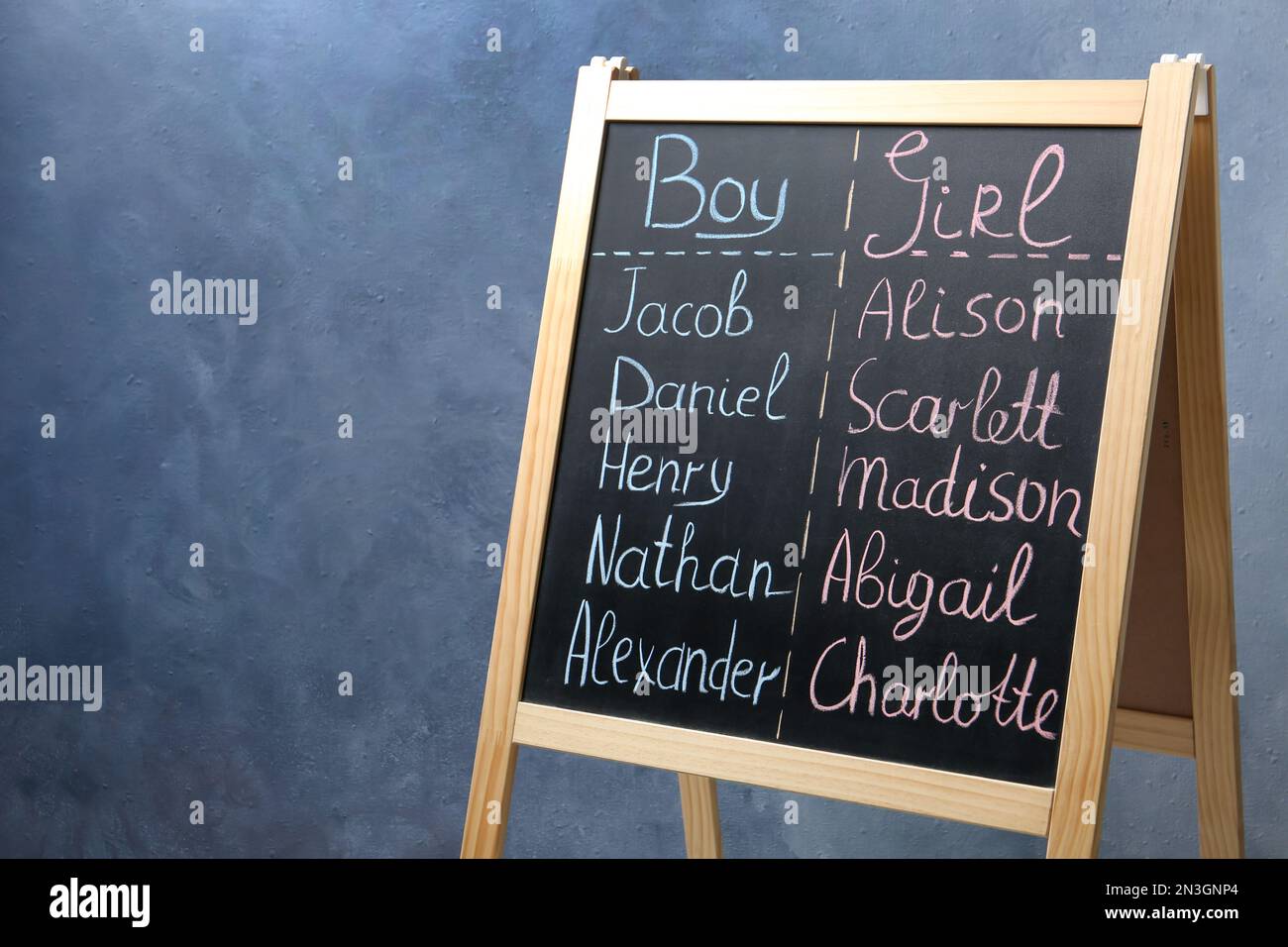 Chalkboard stand with baby names on blue background Stock Photo - Alamy