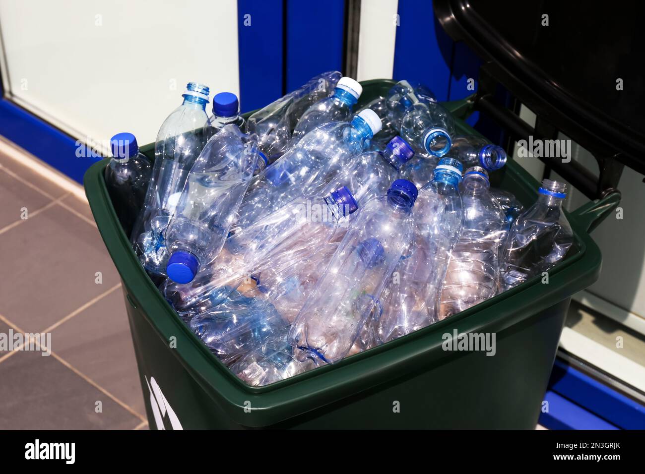 Many used plastic bottles in trash bin outdoors, closeup. Recycling ...