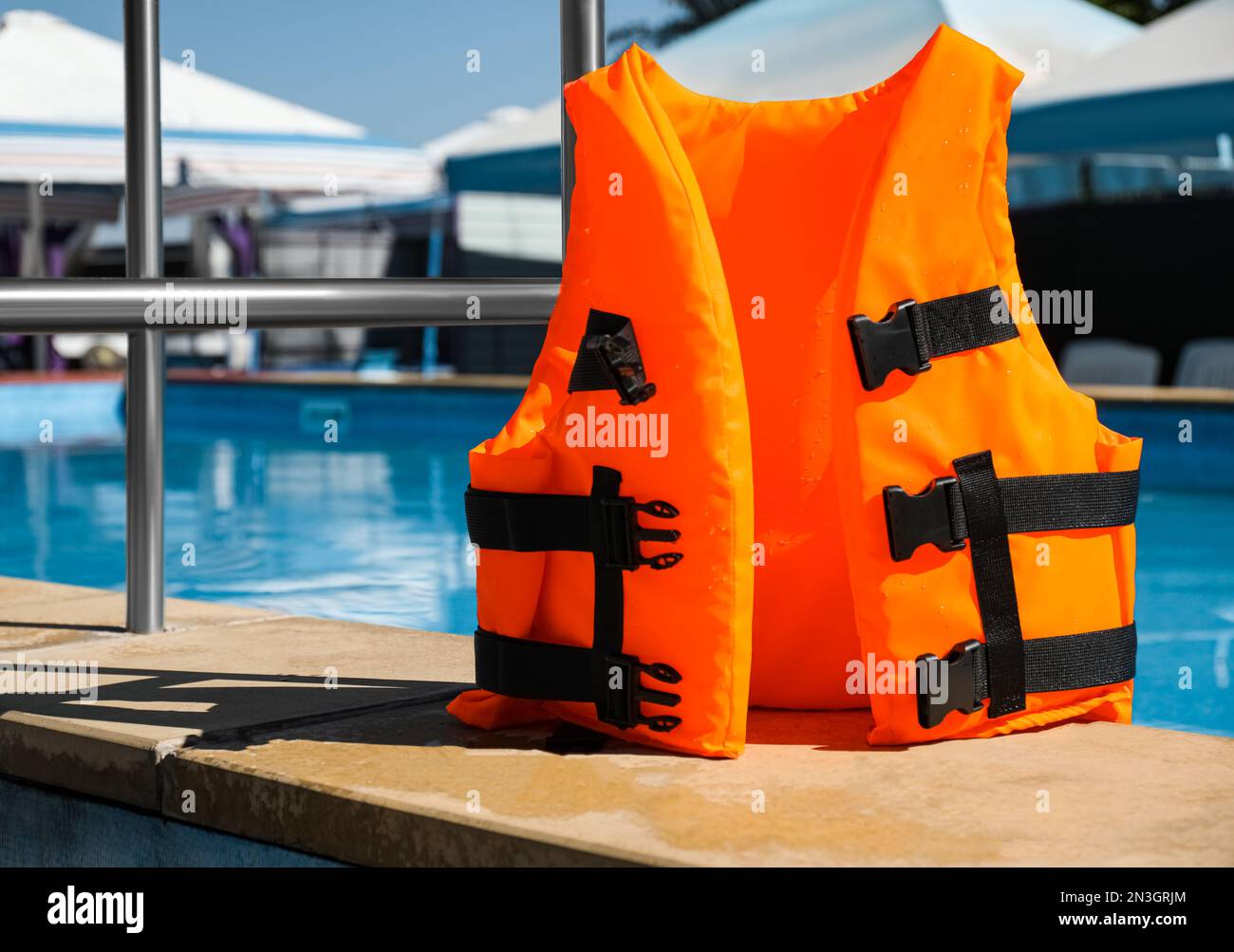Bright orange life jacket near swimming pool Stock Photo - Alamy