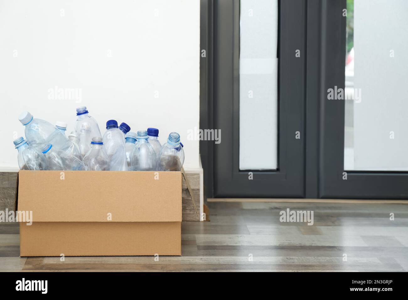 Cardboard box with used plastic bottles near entrance door in hallway ...