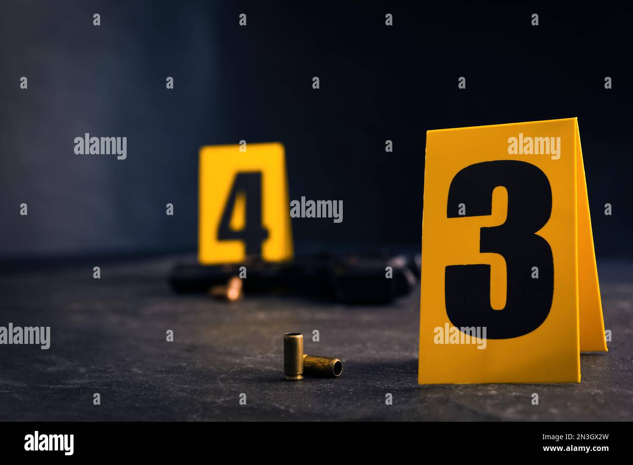 Shell casings and evidence marker on black slate table, closeup. Crime ...