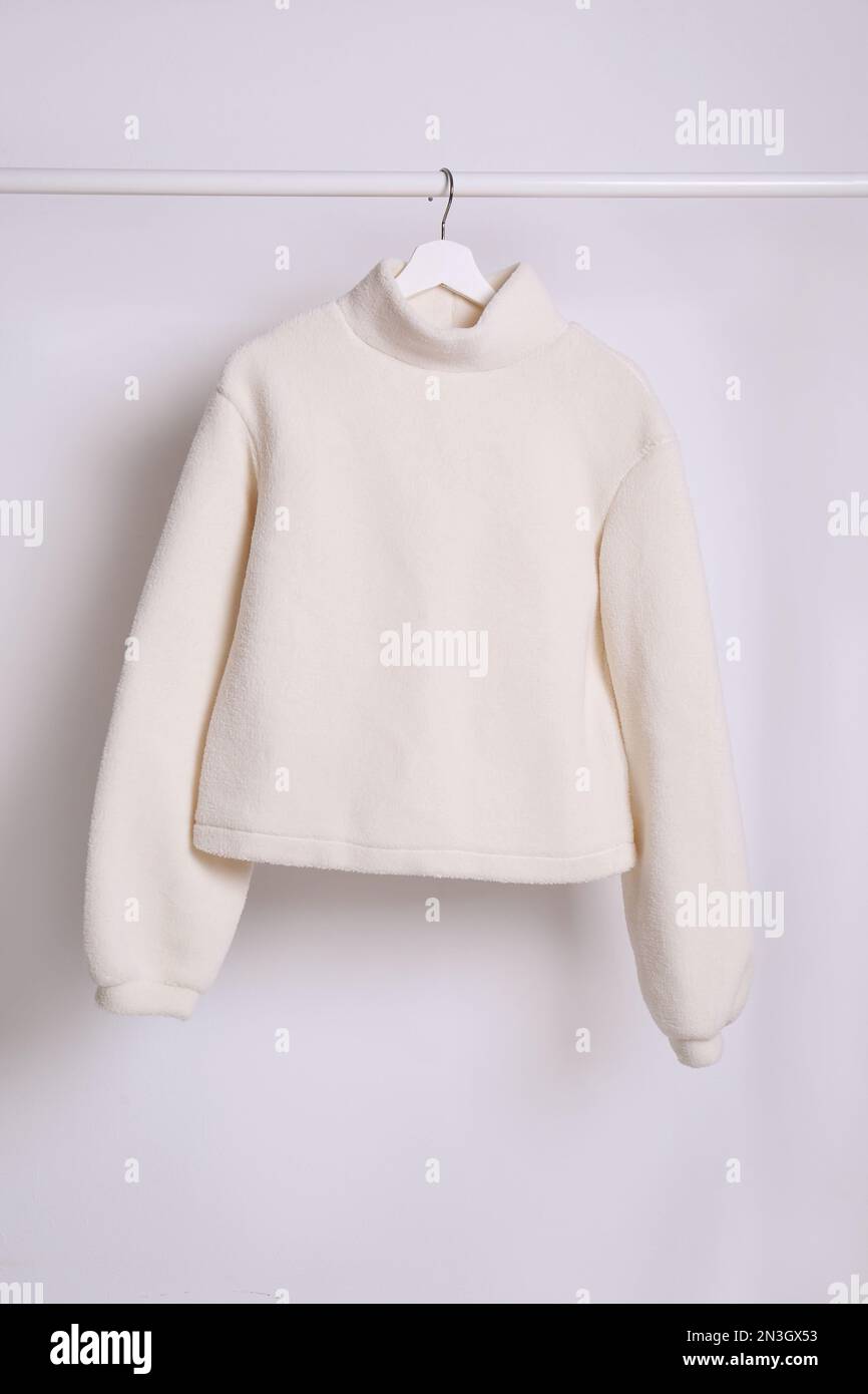 Warm sweater hanging on rack against white background Stock Photo - Alamy