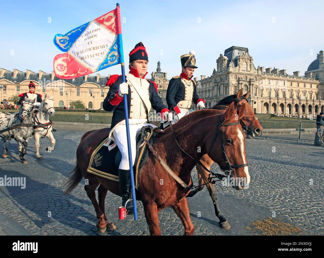 Men wearing Empire uniforms parade on horses, at the Le Louvre in Paris ...