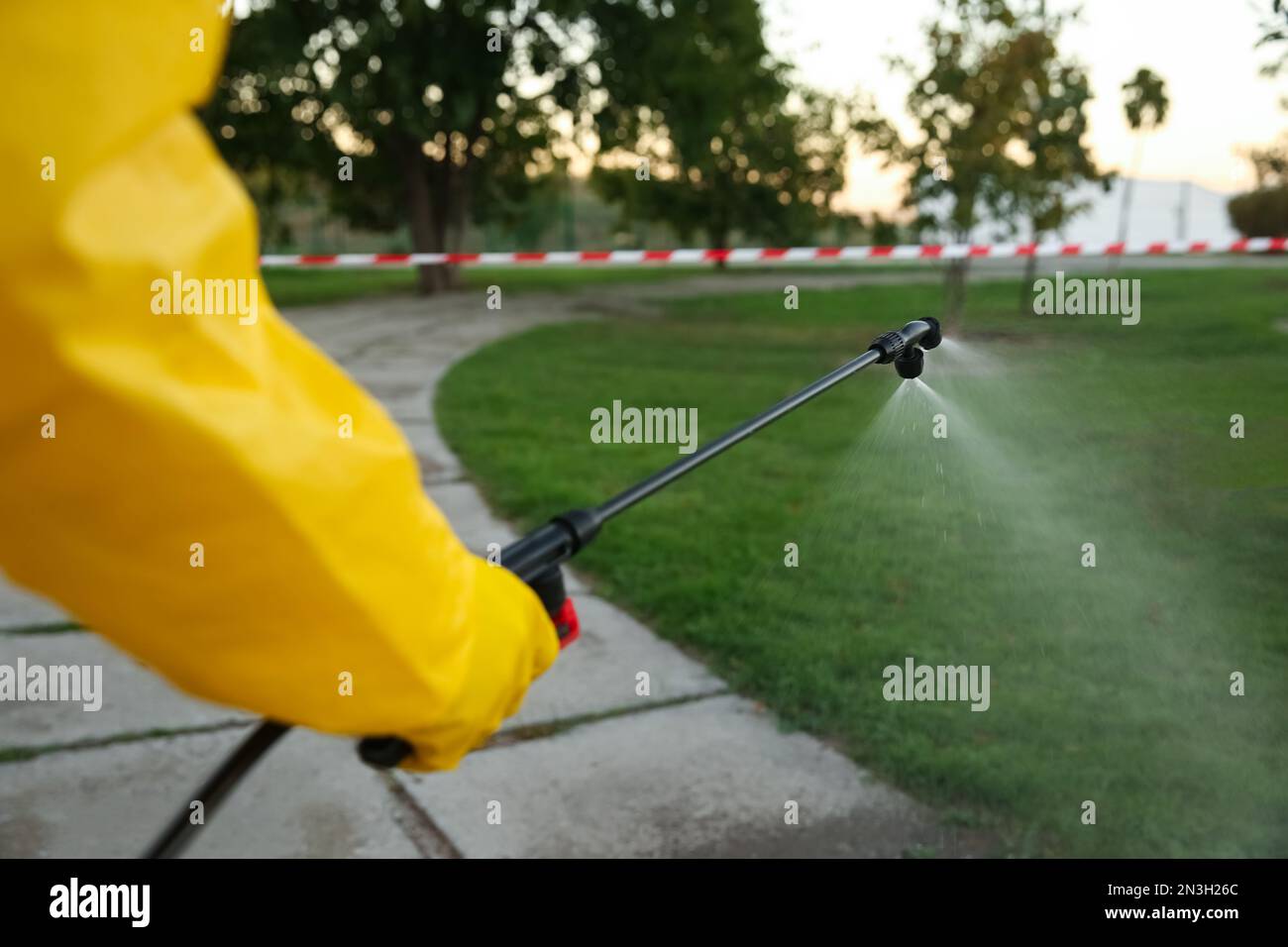 Person in hazmat suit disinfecting street with sprayer, closeup ...
