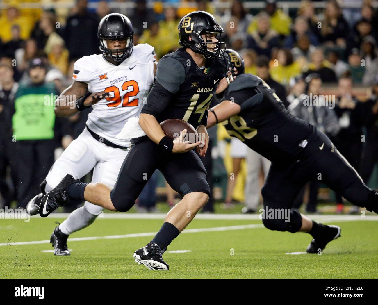 Baylor quarterback Bryce Petty (14) keeps the ball and runs under pressure from Oklahoma State's ...