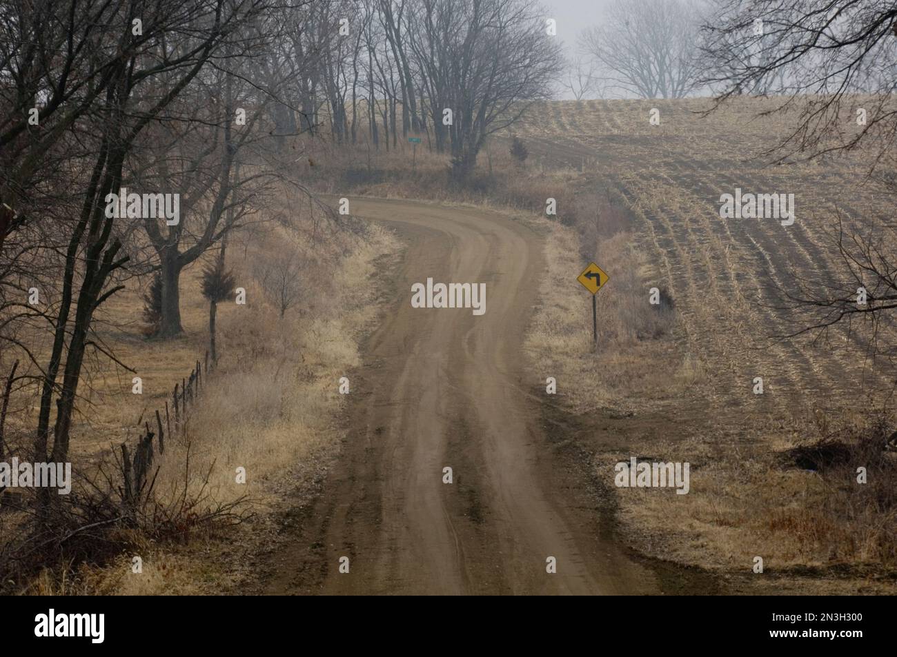 Muddy road leading through a foggy countryside with a road sign warning ...