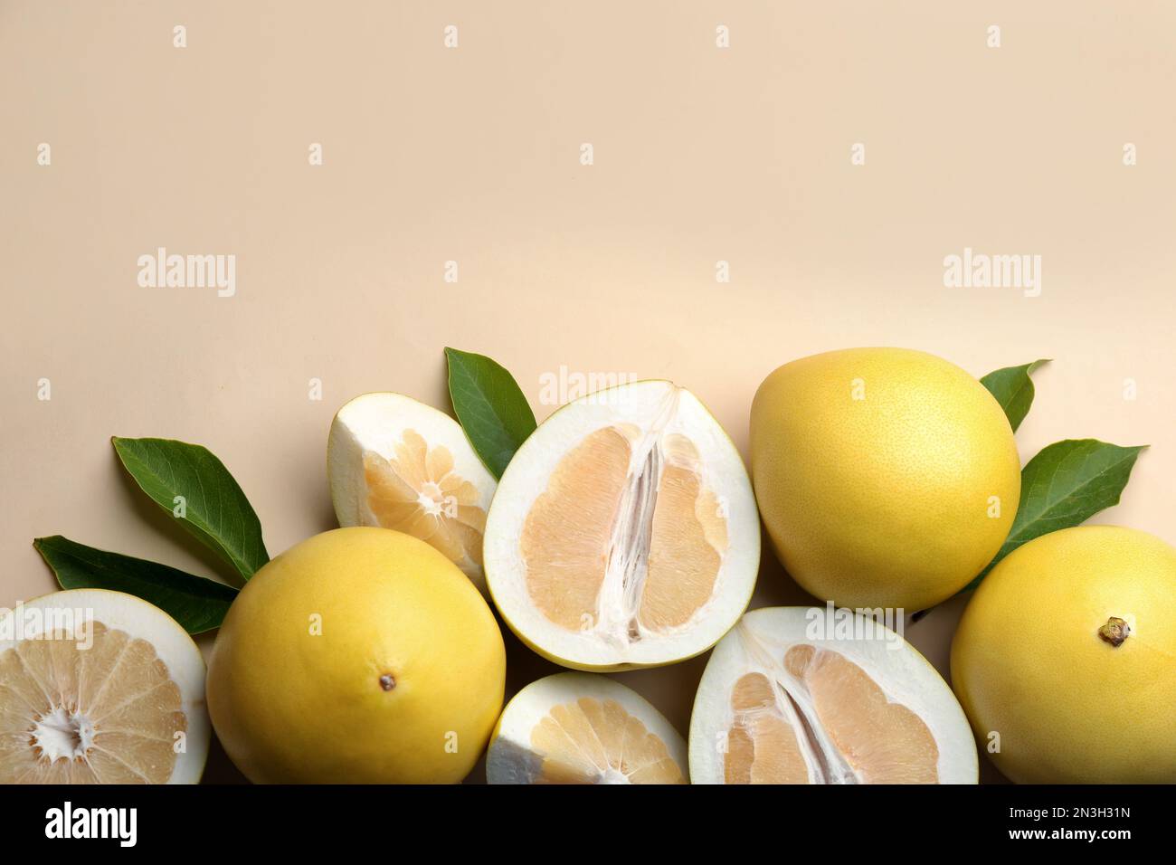 Fresh cut and whole pomelo fruits with leaves on beige background, flat ...