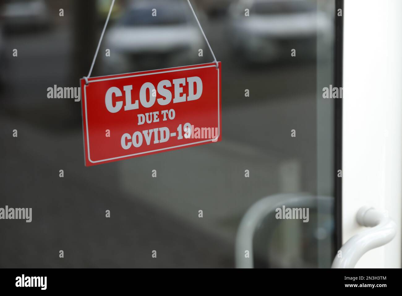 Red sign with words "Closed Due To Covid-19" hanging on glass door ...