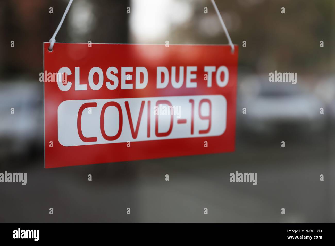 Red sign with words "Closed Due To Covid-19" hanging on glass door ...