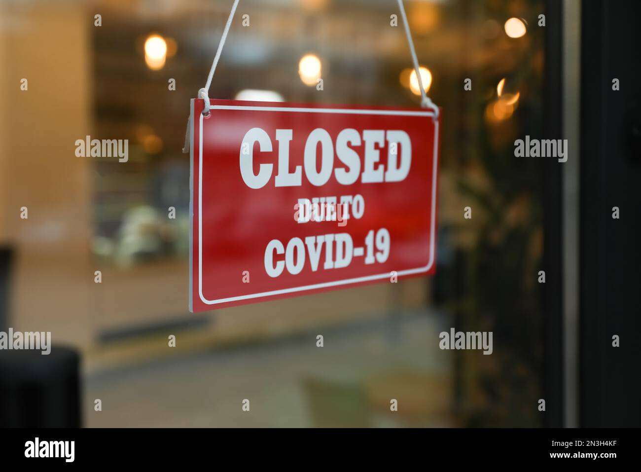 Red sign with words "Closed Due To Covid-19" hanging on glass door ...