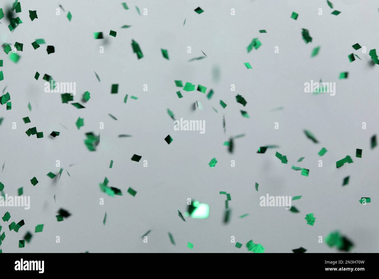 Shiny green confetti falling down on light grey background Stock Photo ...