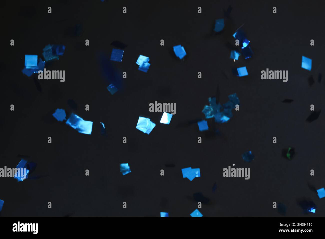 Shiny blue confetti falling down on black background Stock Photo - Alamy