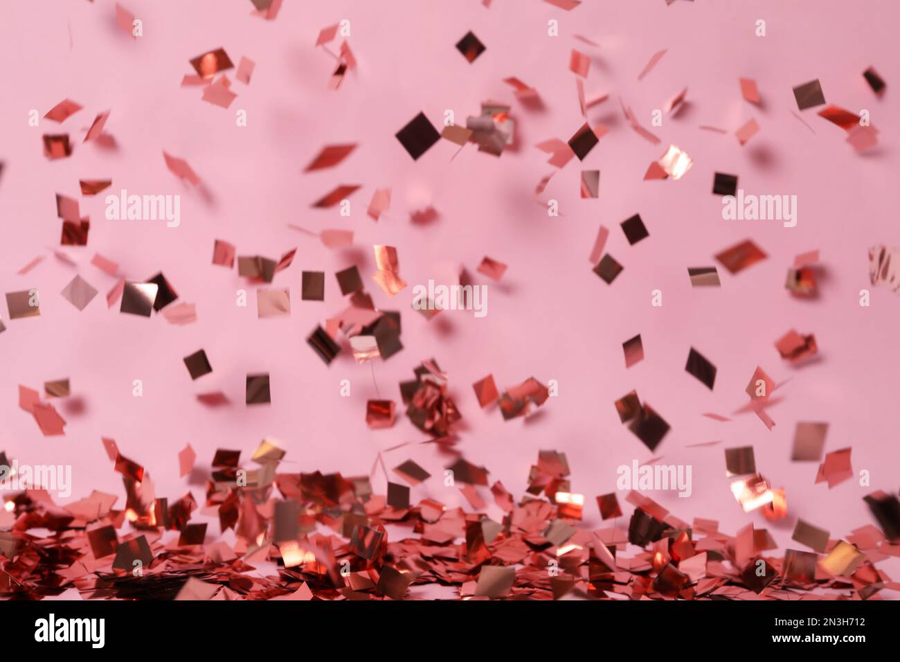 Shiny confetti falling down on pink background Stock Photo - Alamy