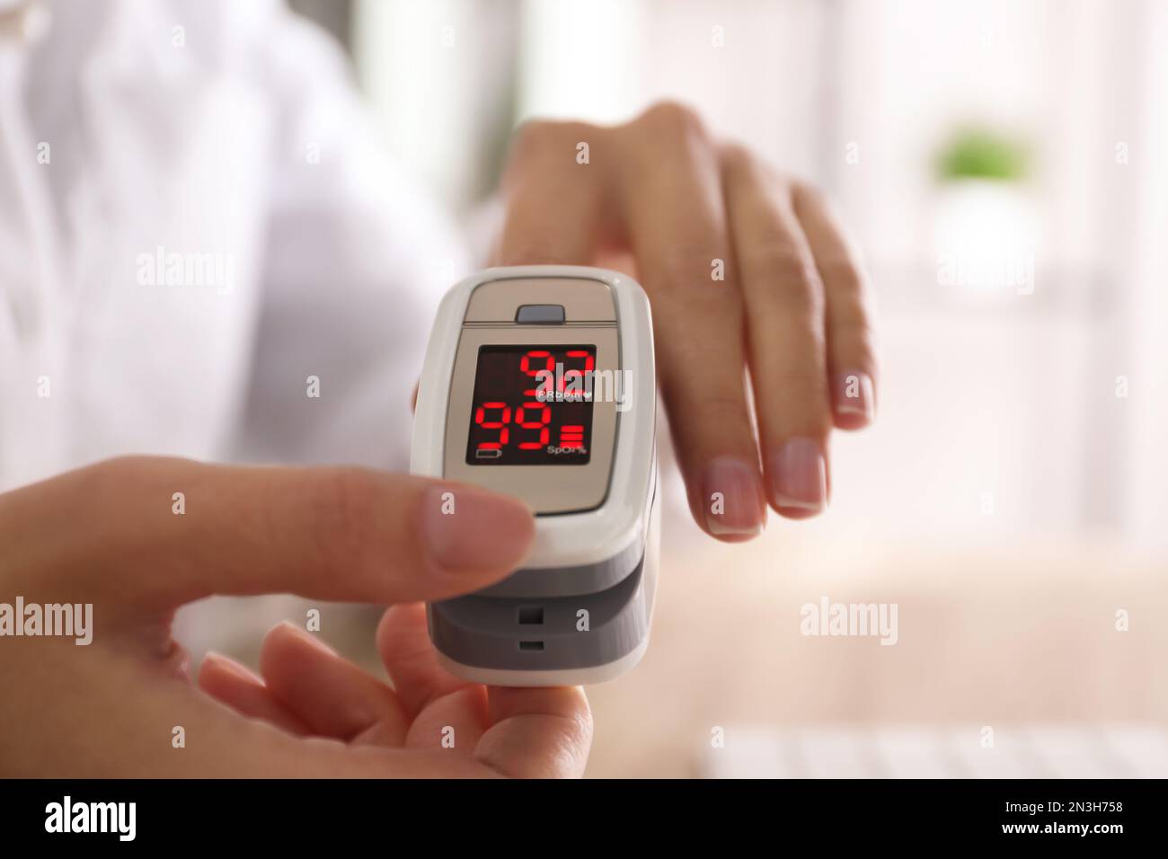 Woman measuring oxygen level with modern fingertip pulse oximeter at ...