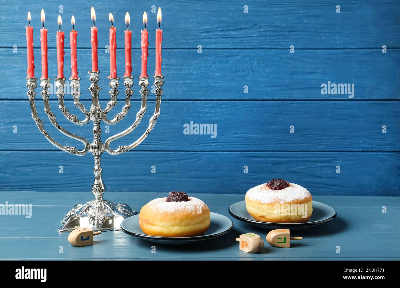 Silver menorah, dreidels with He, Pe, Nun, Gimel letters and sufganiyot ...